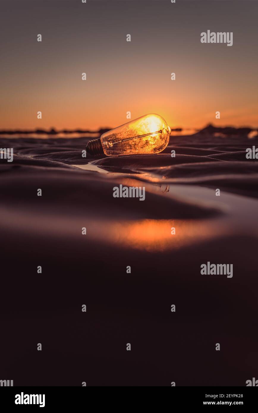 Light bulb in the sand with the sun illuminating it at sunset Stock ...
