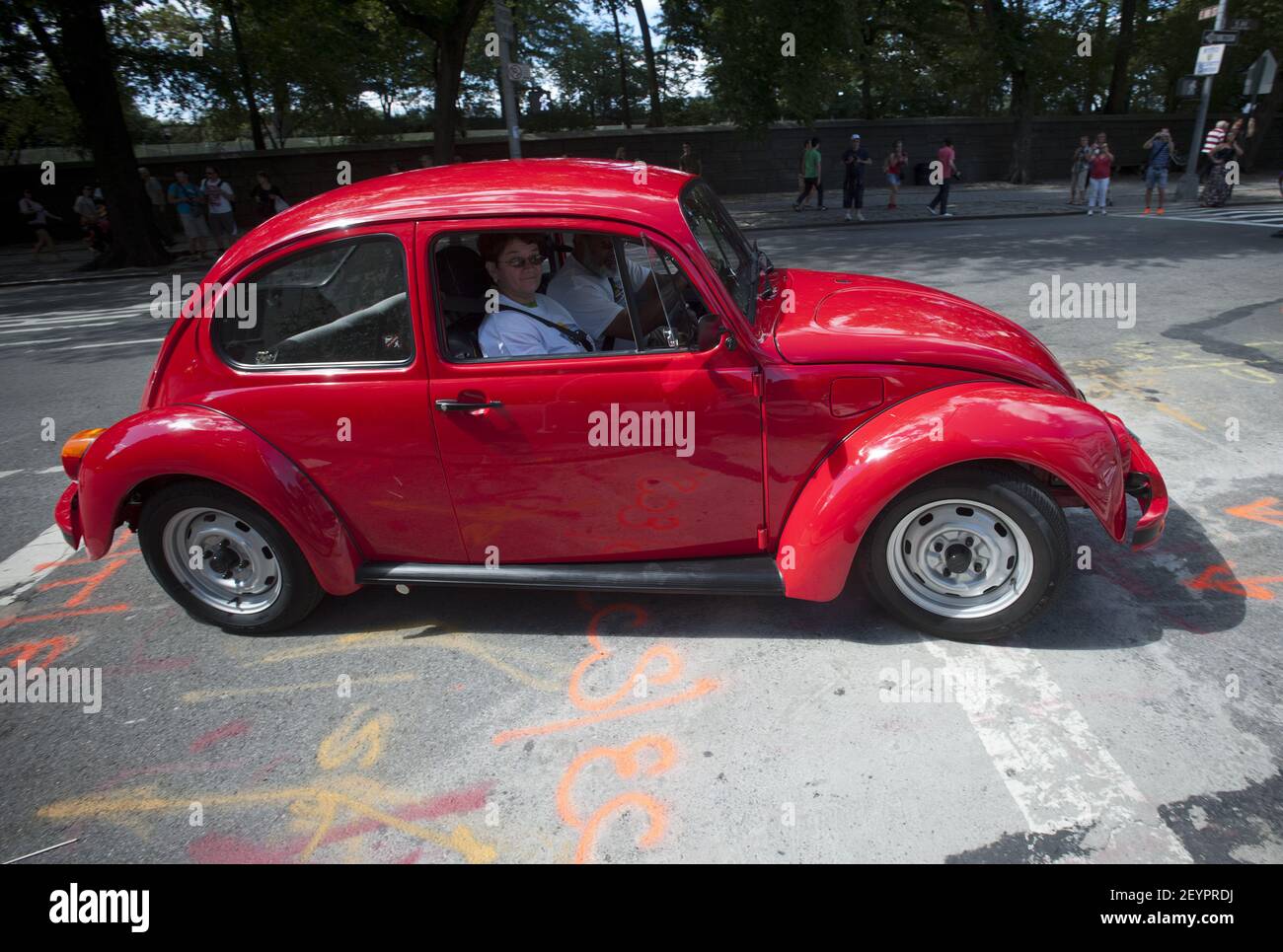 A cherry red restored classic Volkswagen beetle turns a corner on Fifth ...