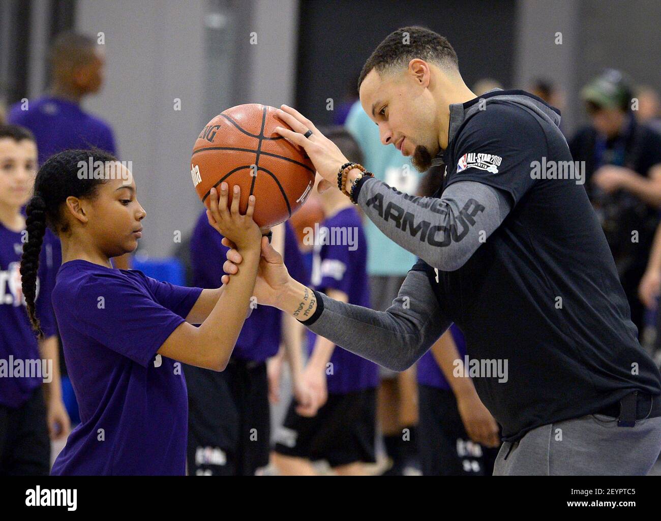 Golden State Warriors guard Stephen Curry, right, helps a student with ...