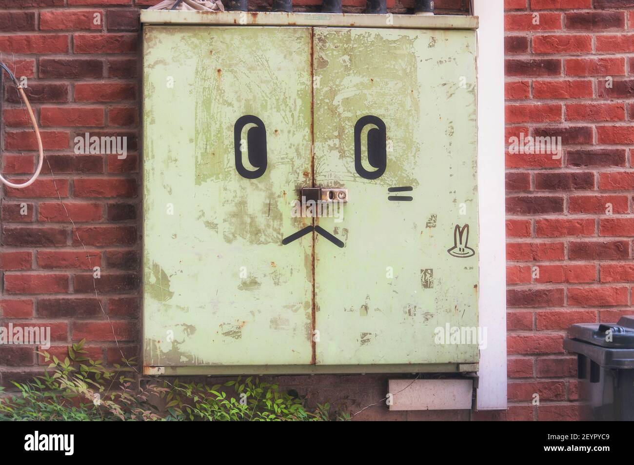 A weathered electrical panel on the outside of a brick building inside ...
