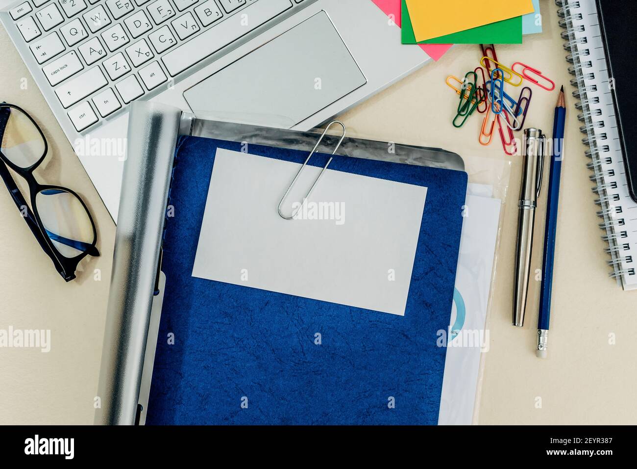 A top view closeup of a laptop, notebook, glasses, paper clips and ...