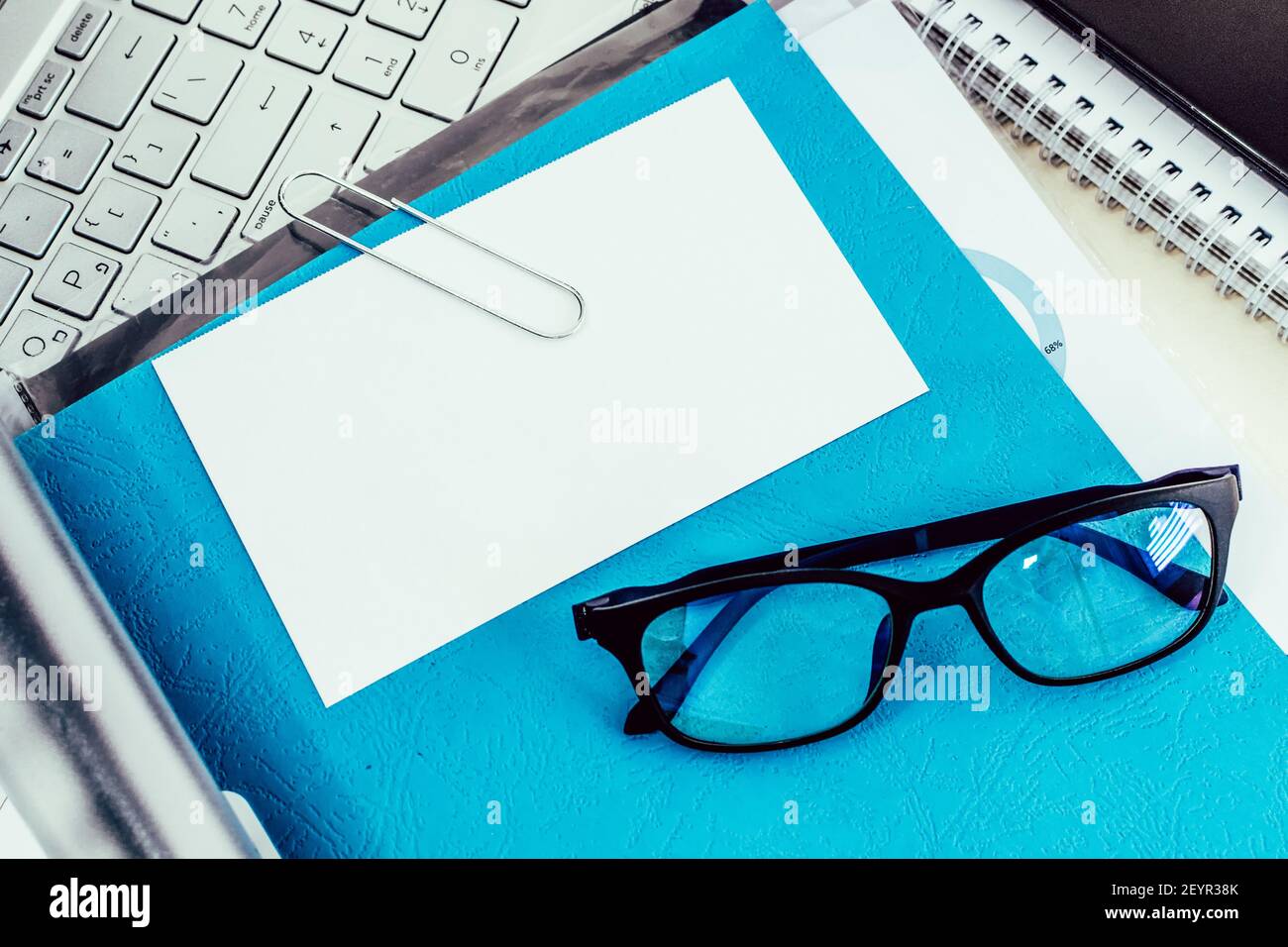 A top view closeup of a laptop, notebook, glasses, paper clips on the ...