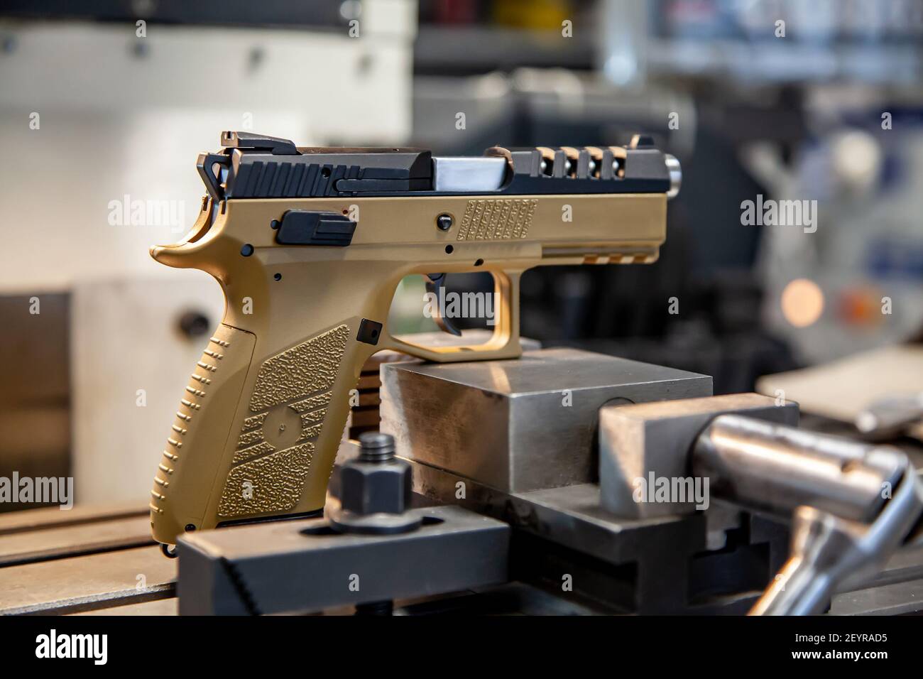 A modern pistol with a beige grip on a work table in a workshop ...