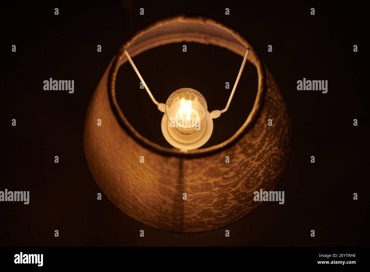 Incandescent light bulb in round lampshade glowing in dark. Extremely ...