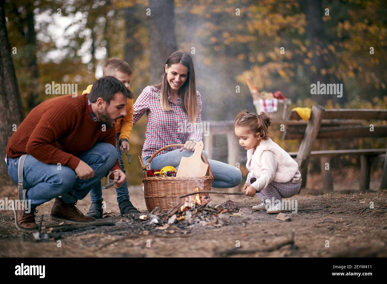 Young family on picnic in forest preparing fire Stock Photo - Alamy