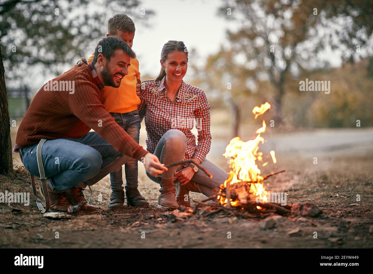 Happy family with little son light fire in wood Stock Photo - Alamy