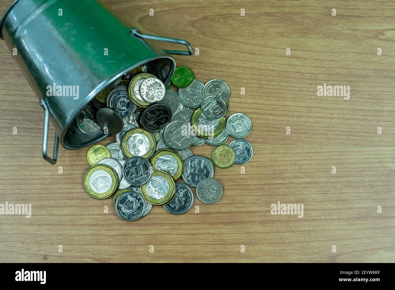 Full of money coins in a tin bucket on blue background for investment ...