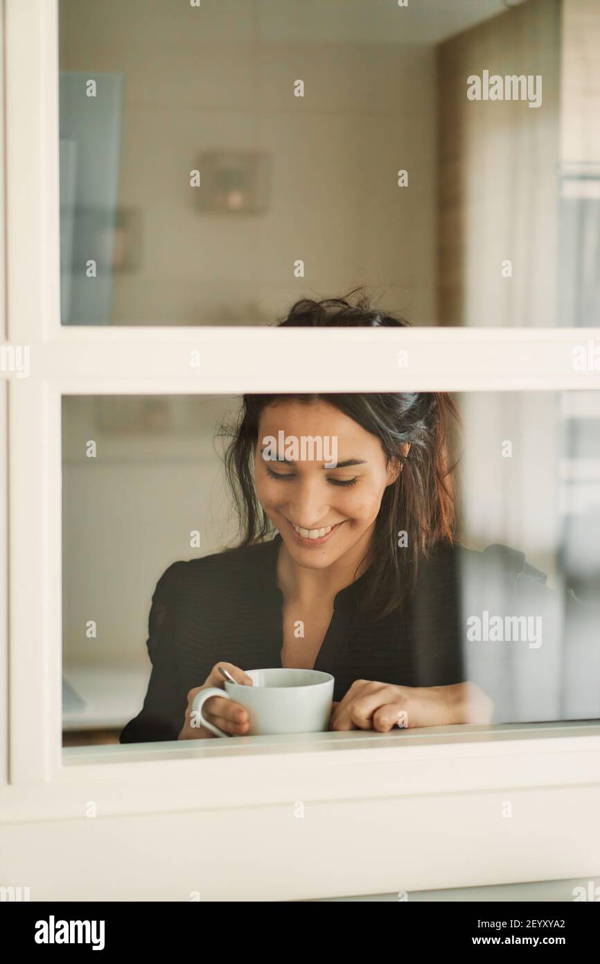 A vertical shot of a Latin woman drinking morning coffee near the window Stock Photo - Alamy
