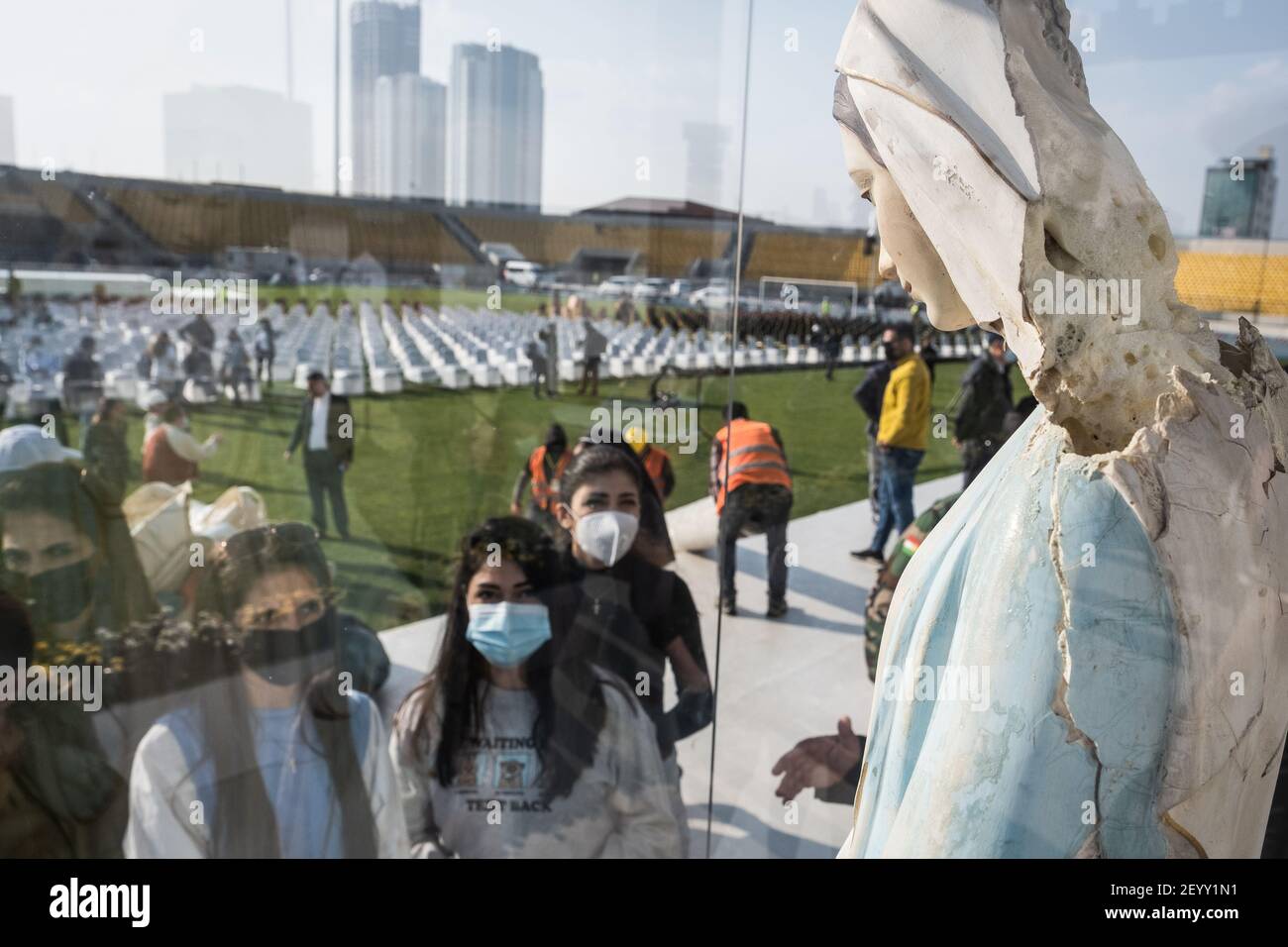 Erbil, Iraq. 06th Mar, 2021. People look at a restored statue of Virgin ...