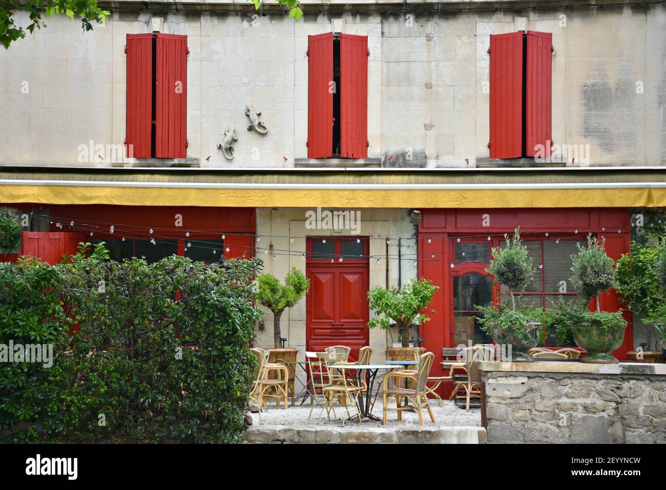 Provençal restaurant facade with a weathered stucco wall and bright red ...