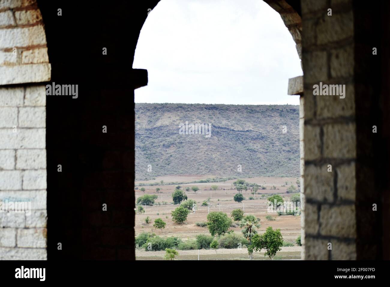 A field with some trees visible through the arc-shaped wall of a ...