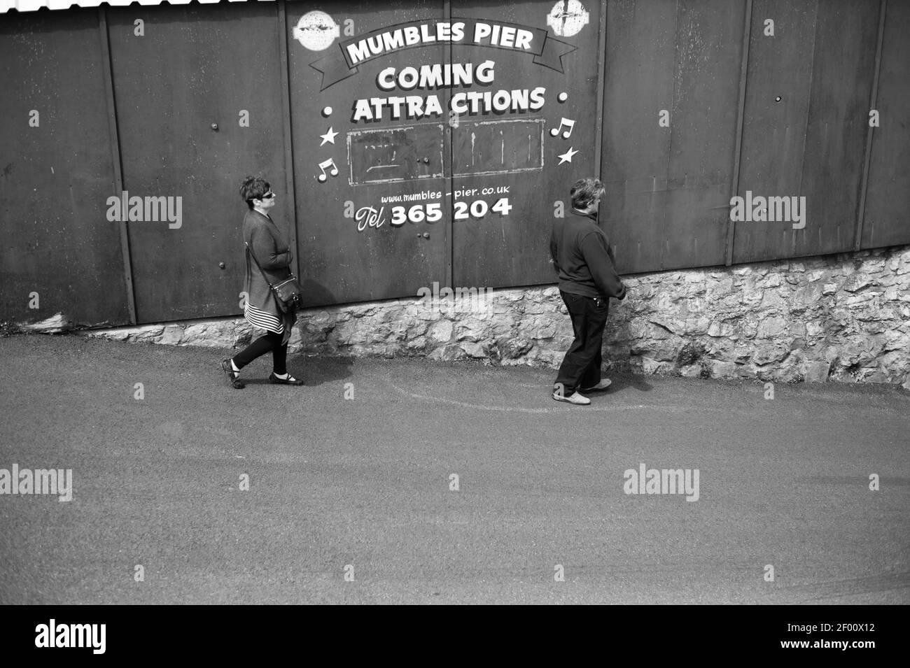 Two people passing advertisement Stock Photo - Alamy