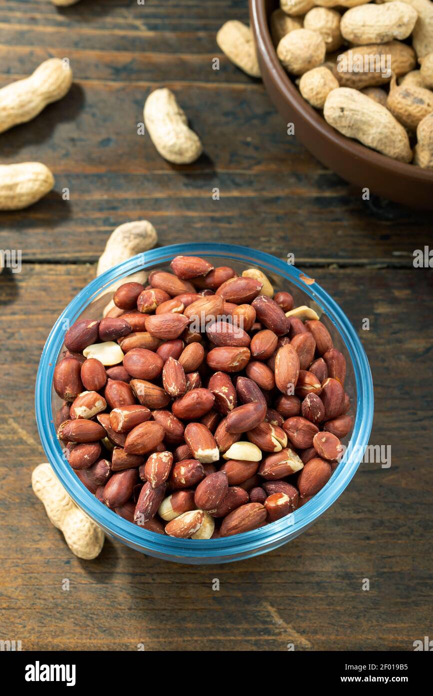 Peanuts in their husks in a glass bowl and peanuts in their skins are ...