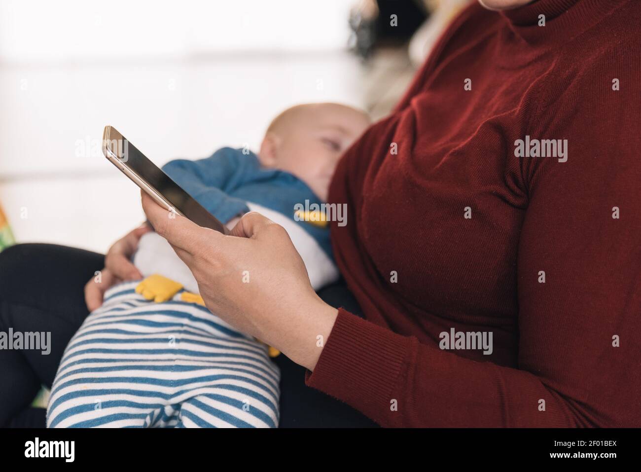 Busy single mother feeding her baby while busy with a call. The newborn ...