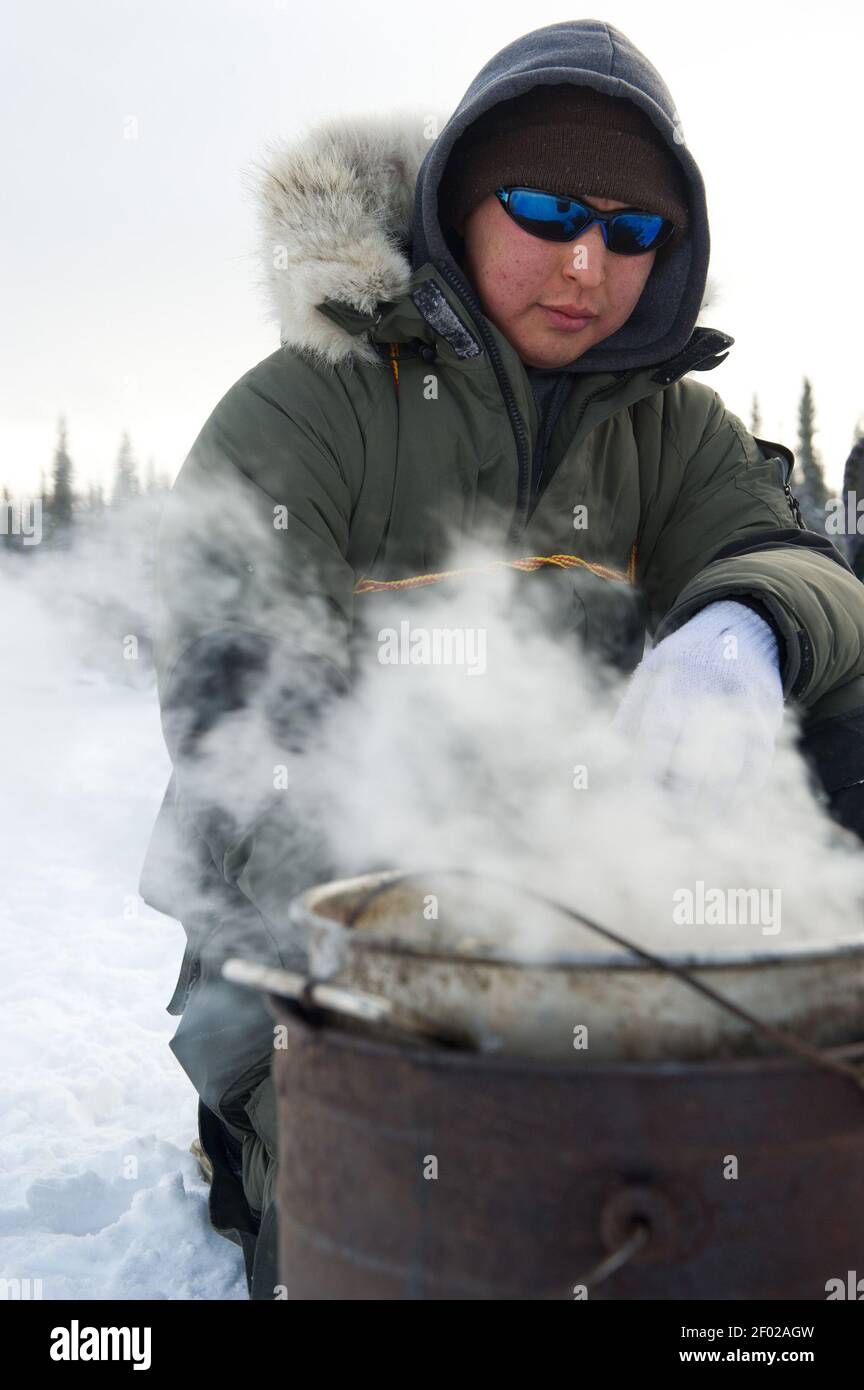 Mike Williams, Jr., cooks dog foot at the Nikolai checkpoint in Alaska ...