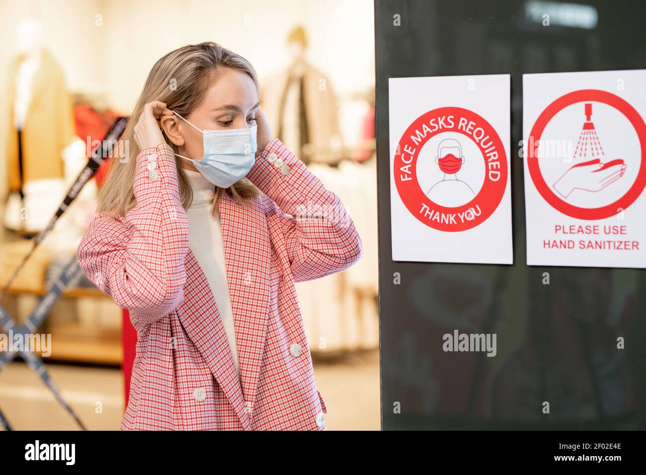 Woman putting on a mask when she entering the mall Stock Photo - Alamy