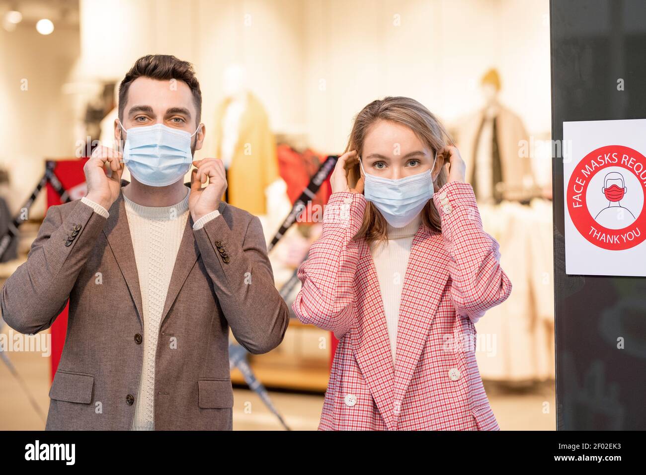Portrait of young couple looking at camera while putting on the masks ...