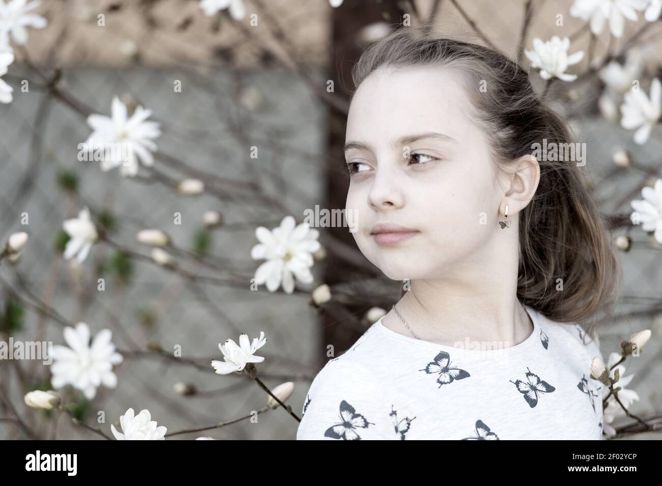 Cute spring fashion girl under blossom magnolia tree Stock Photo - Alamy