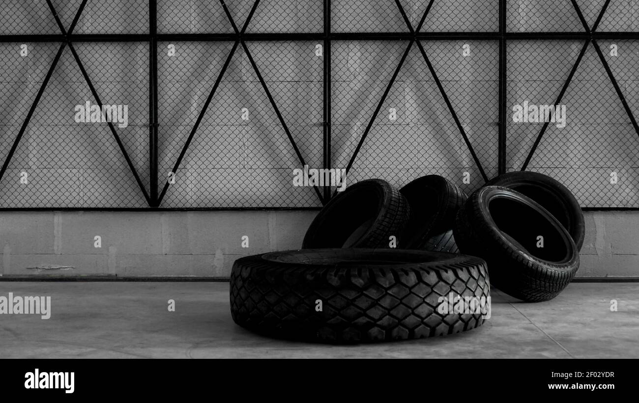Tire warehouse. Four tires on the concrete floor. Black mesh on the ...