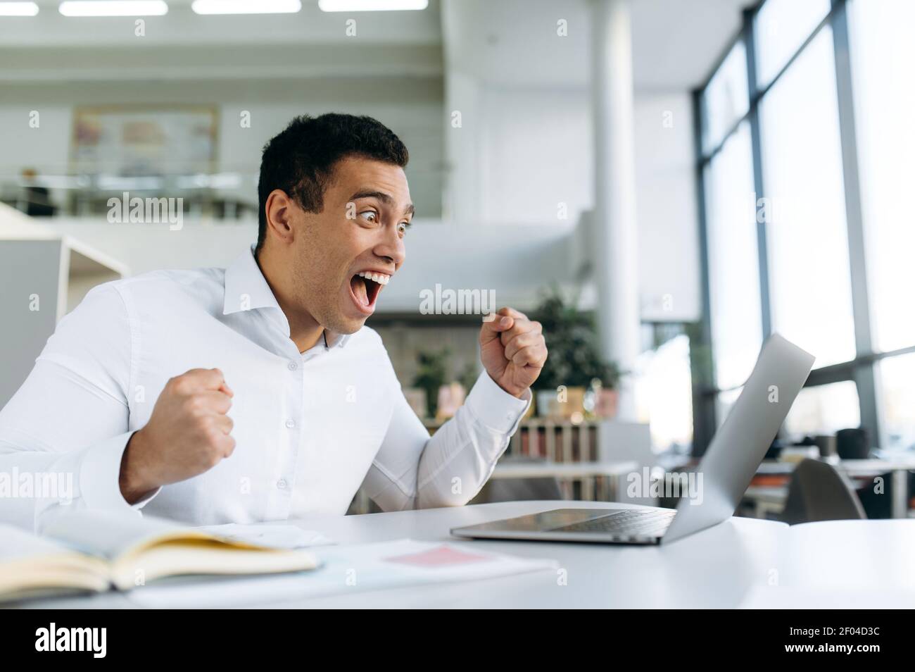 Surprised hispanic male sitting at the work desk, with excited face ...