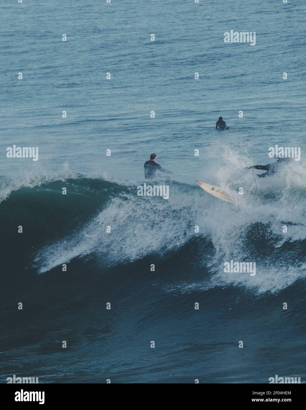 A vertical shot of surfers falling form their boards on the wave Stock ...
