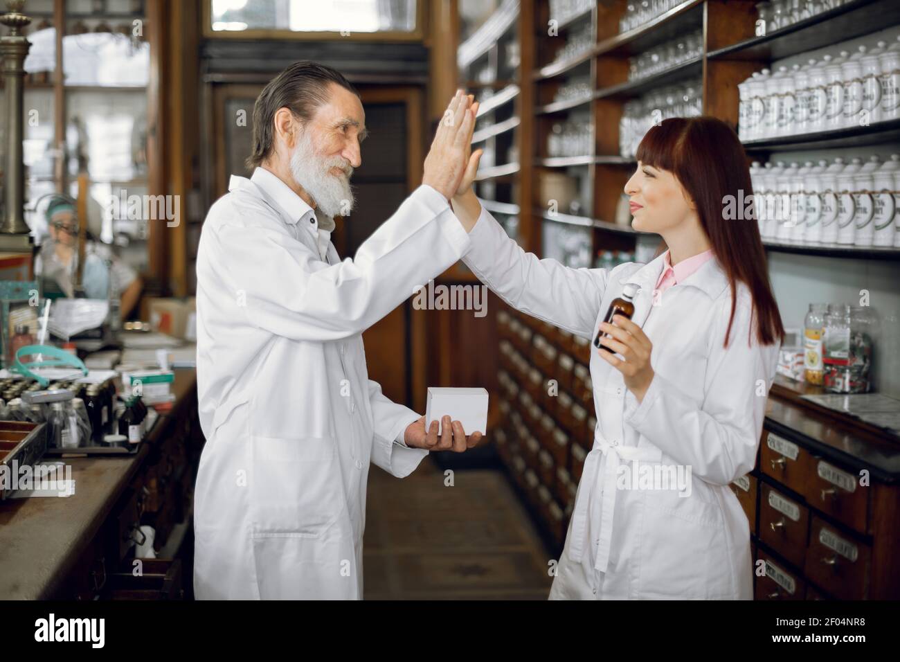Two happy colleages pharmacists, senior man and young woman, working in ...