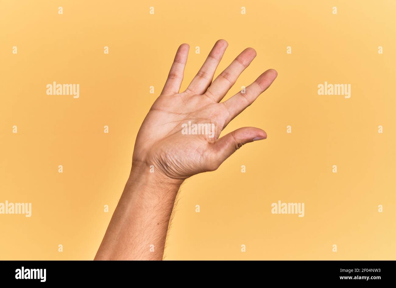 Arm and hand of caucasian man over yellow isolated background ...