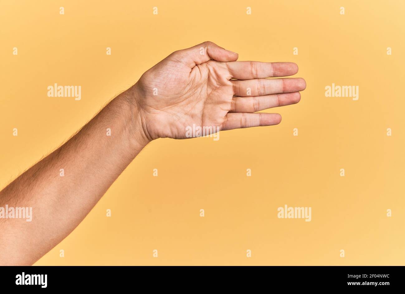 Arm and hand of caucasian man over yellow isolated background ...
