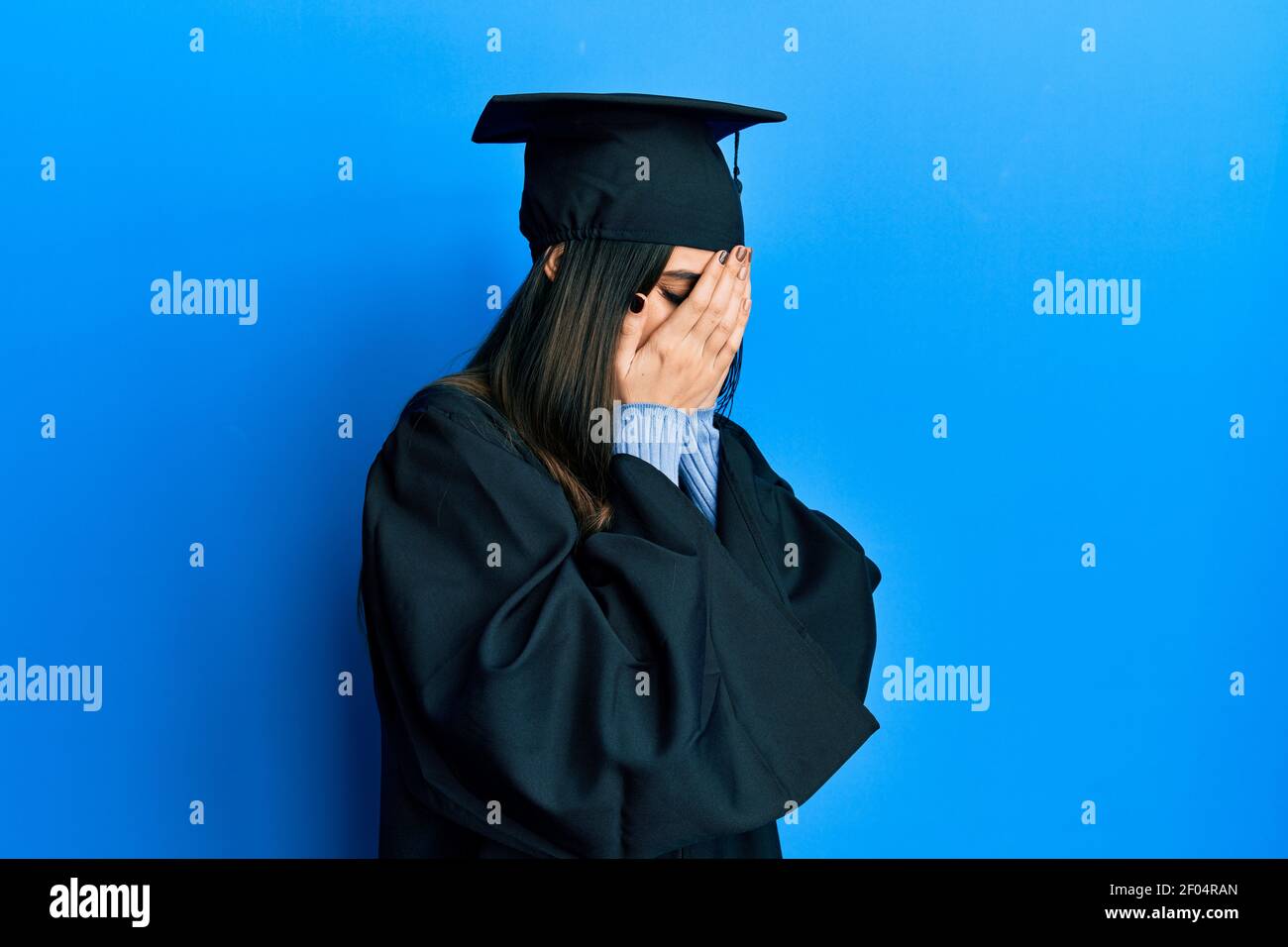 Beautiful brunette young woman wearing graduation cap and ceremony robe ...