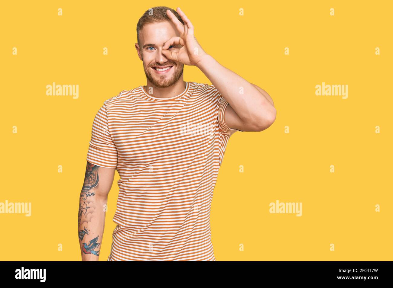 Young irish man wearing casual clothes smiling happy doing ok sign with ...