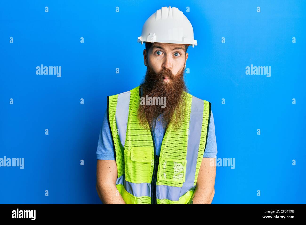 Redhead man with long beard wearing safety helmet and reflective jacket ...