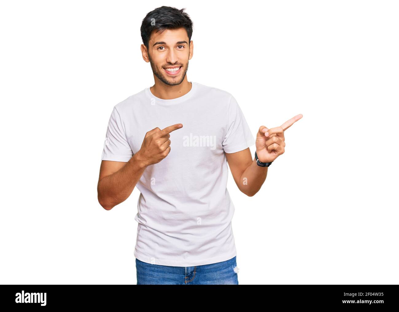 Young handsome man wearing casual white tshirt smiling and looking at ...