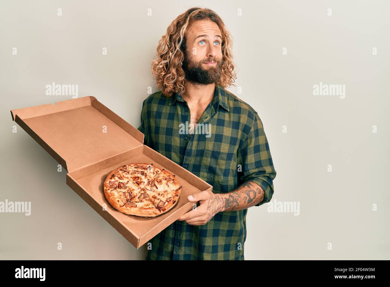 Handsome man with beard and long hair holding italian pizza smiling ...