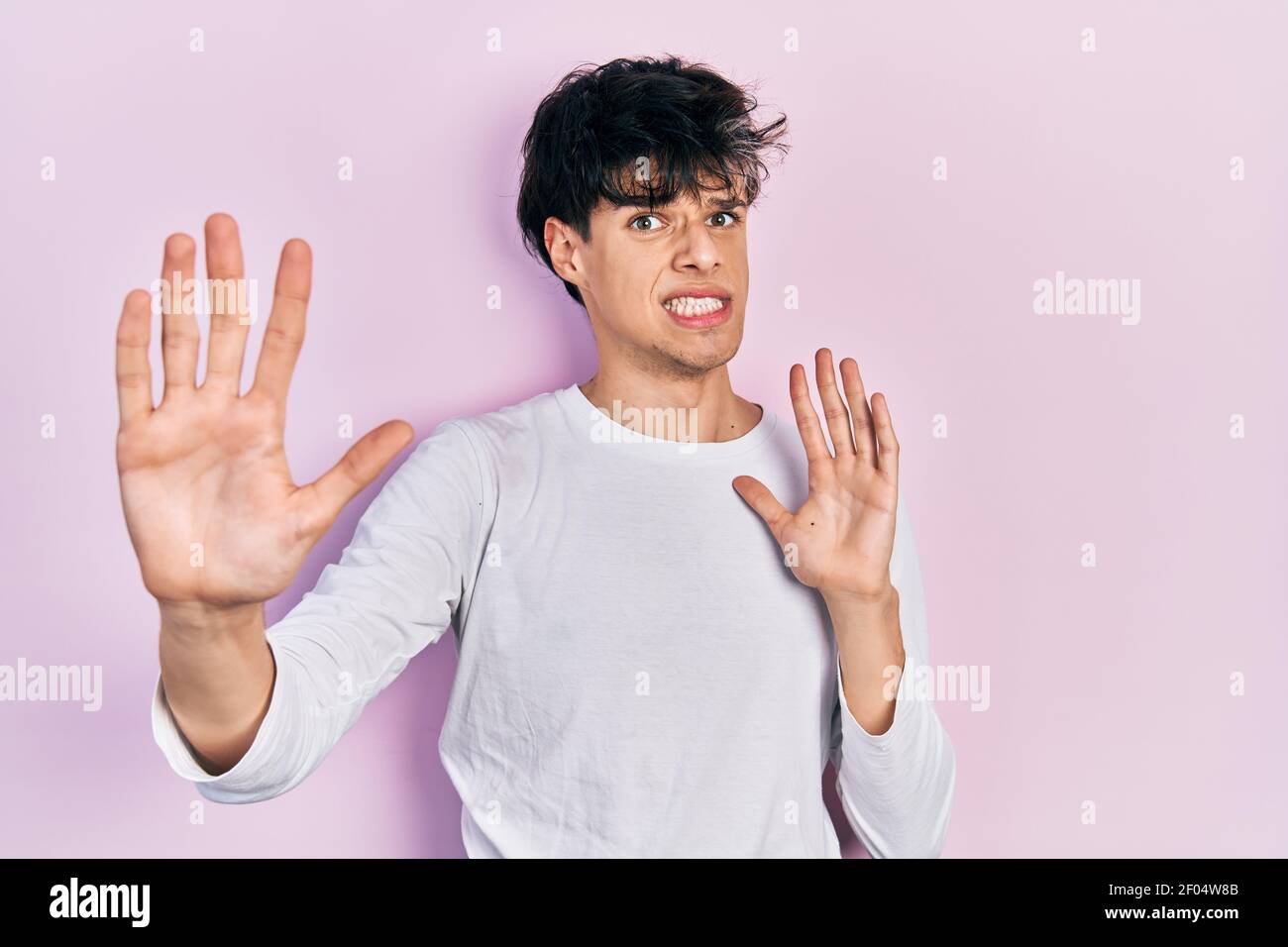 Handsome hipster young man wearing casual white shirt afraid and ...