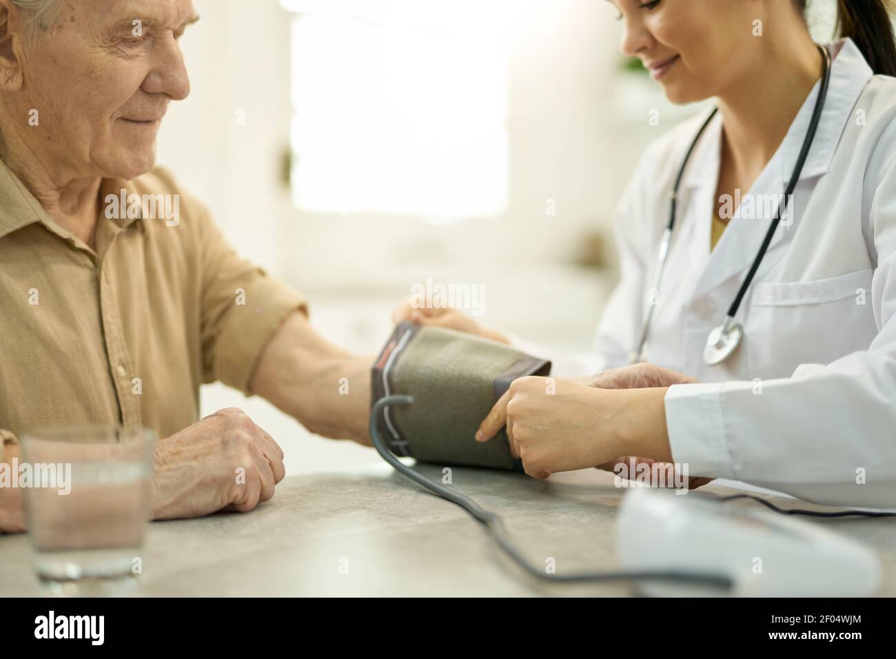 Caring medical doctor putting inflatable cuff of a manometer on arm of ...