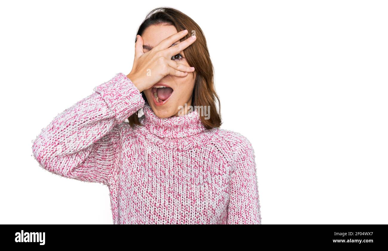 Young caucasian girl wearing wool winter sweater peeking in shock ...