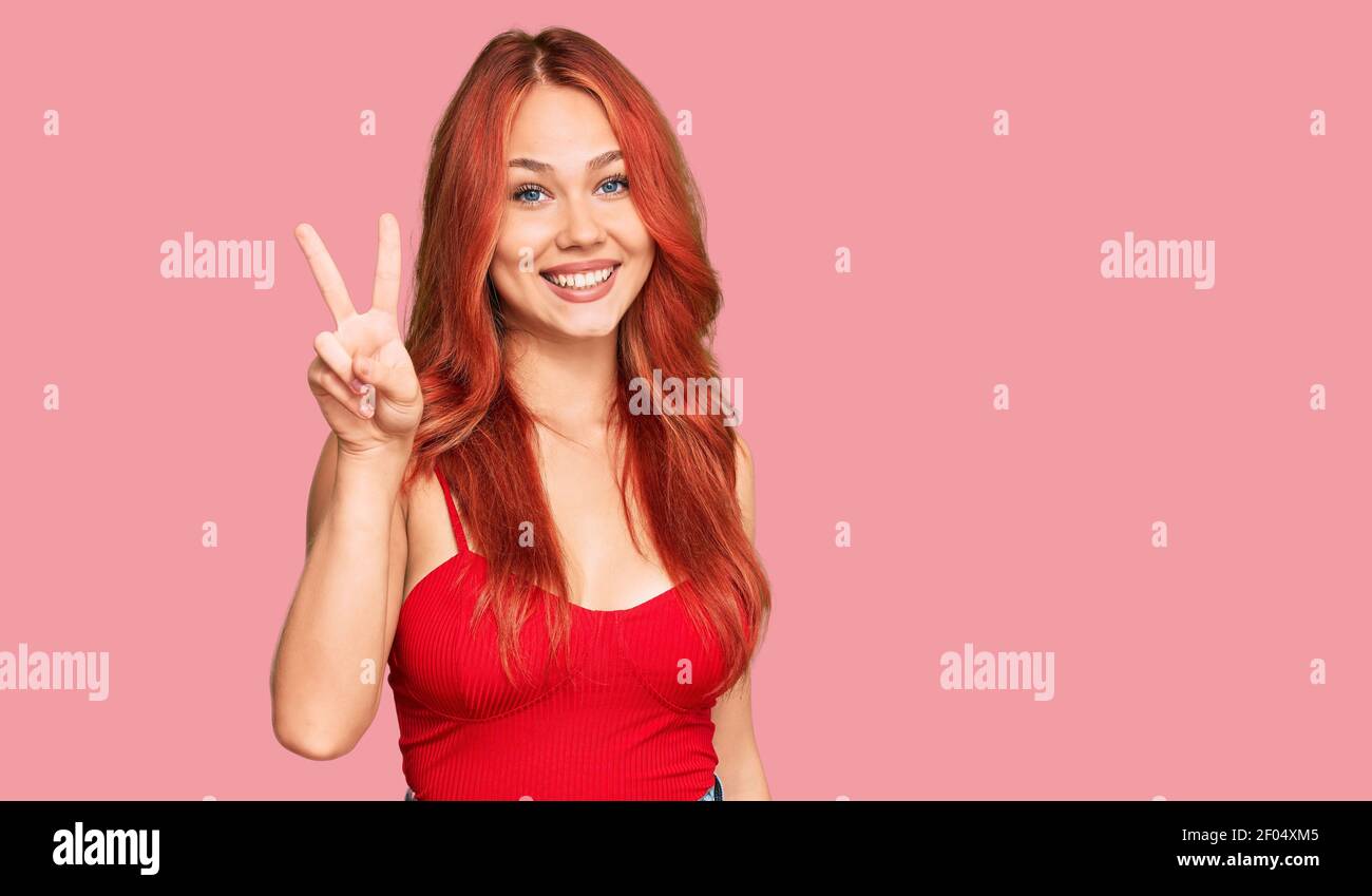 Young redhead woman wearing casual clothes showing and pointing up with ...