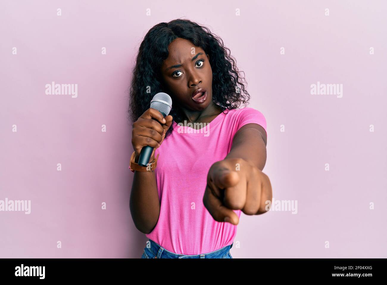 Beautiful african young woman singing song using microphone pointing to ...