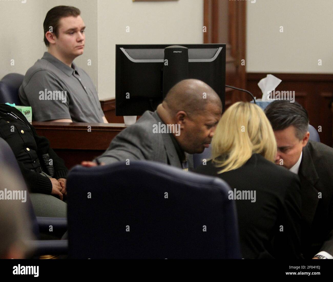Brogan Rafferty, back left, waits on the stand as his defense team ...