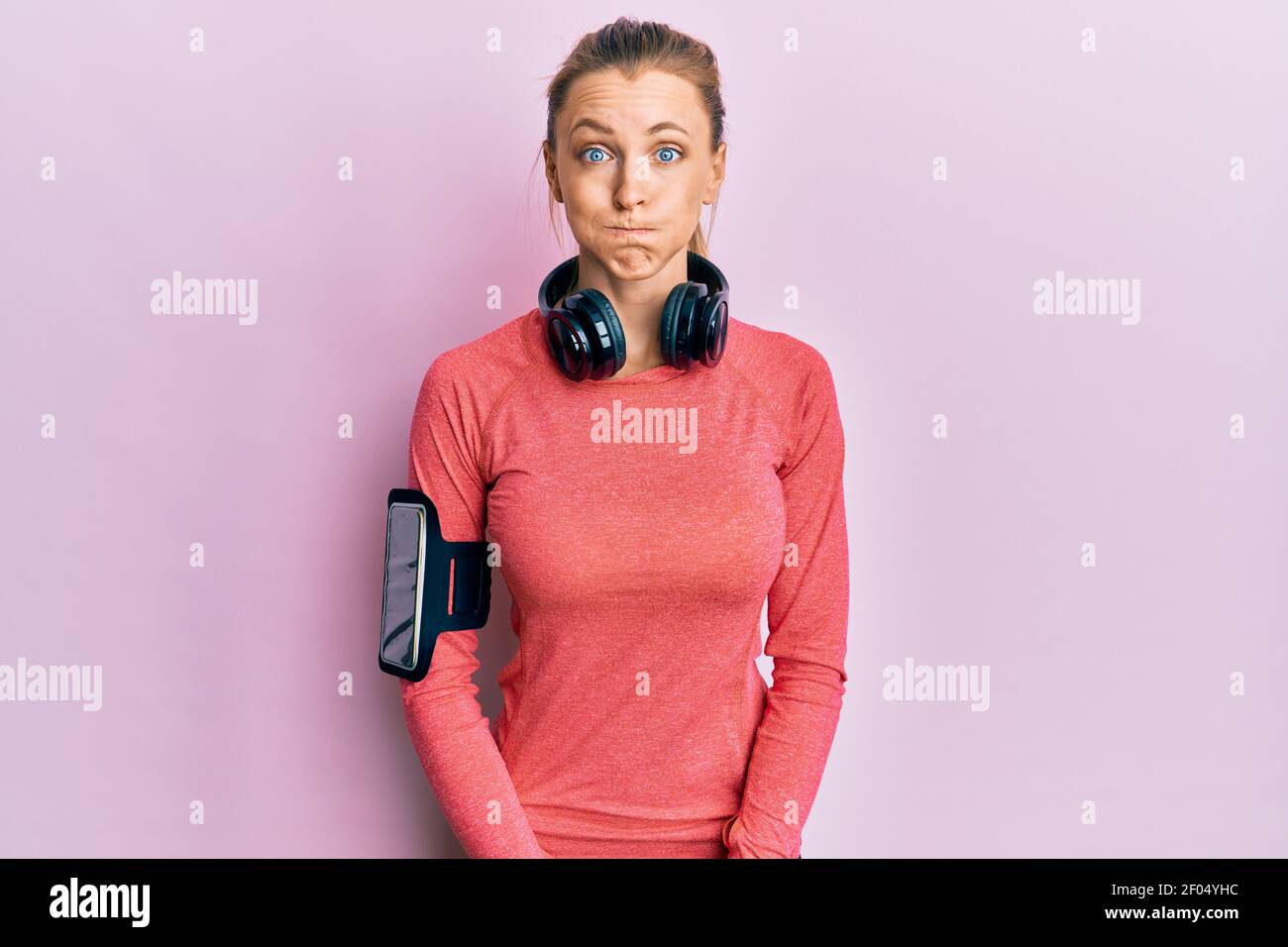 Beautiful caucasian woman wearing sportswear and arm band puffing ...