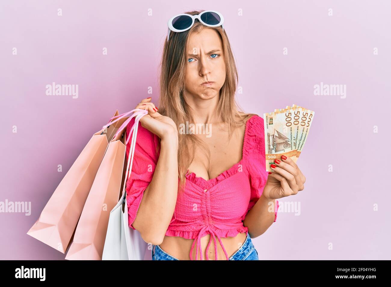 Beautiful caucasian woman holding shopping bags and 500 norwegian krone ...