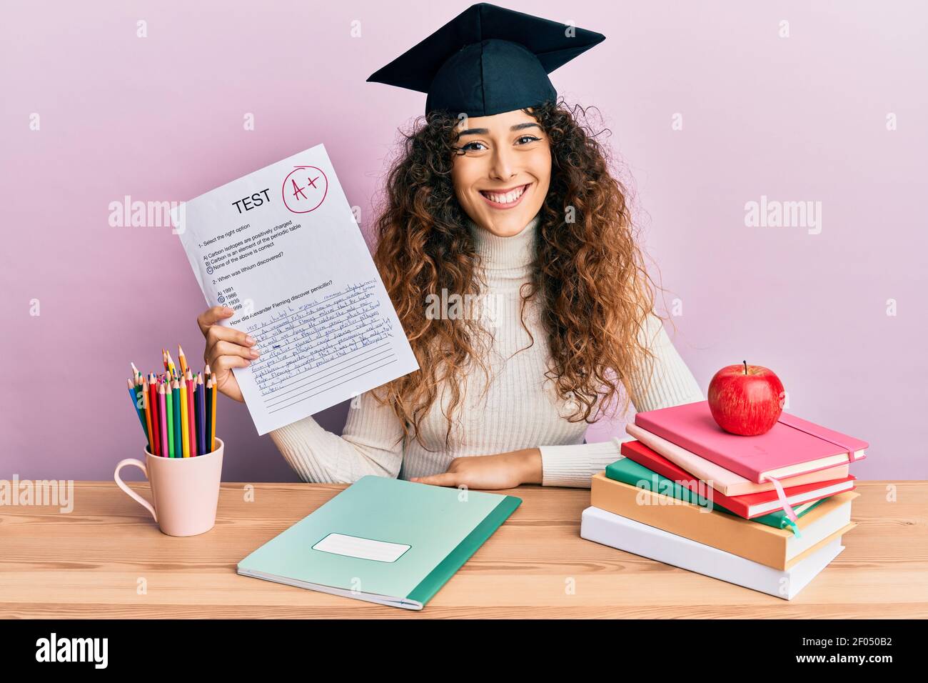 Young hispanic girl wearing graduated hat holding passed test looking ...