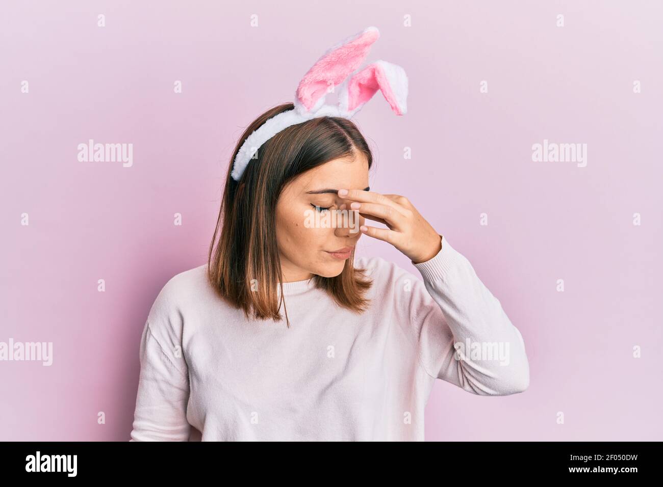 Young beautiful woman wearing cute easter bunny ears tired rubbing nose ...