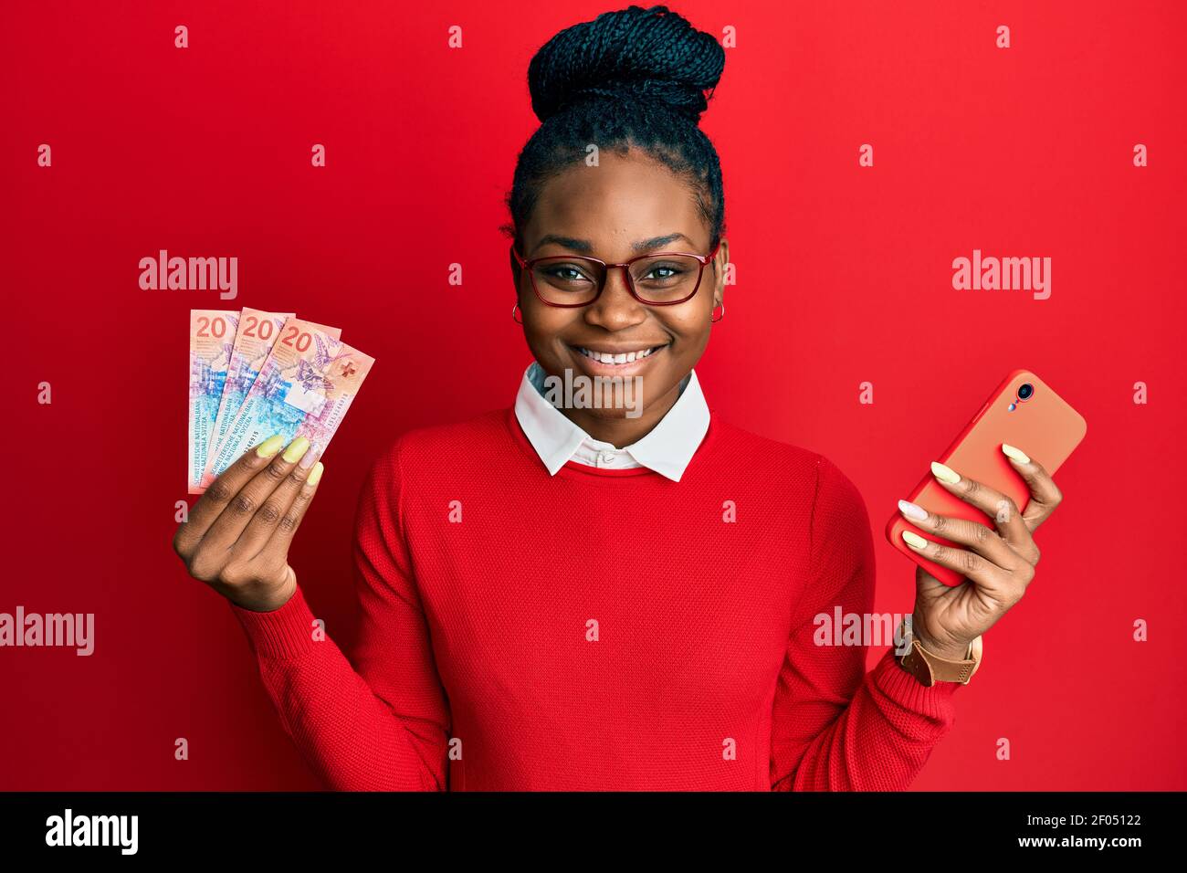 Young african american woman using smartphone holding swiss franc ...