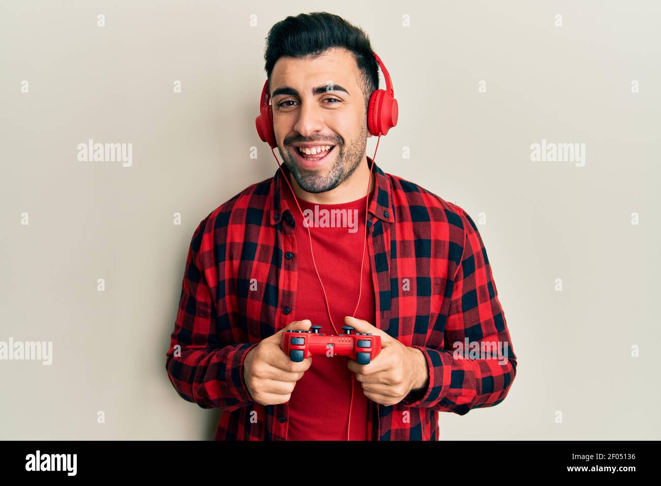 Young hispanic man playing video game holding controller smiling with a ...