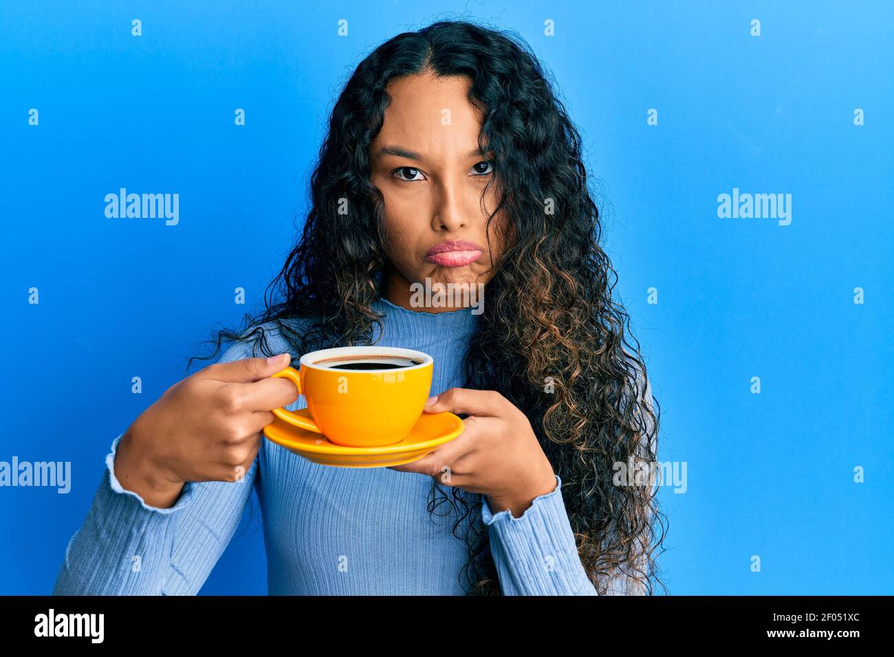 Young latin woman holding coffee depressed and worry for distress ...