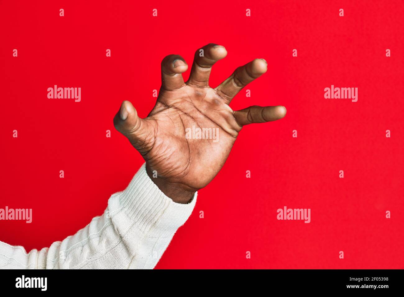 Arm and hand of african american black young man over red isolated ...