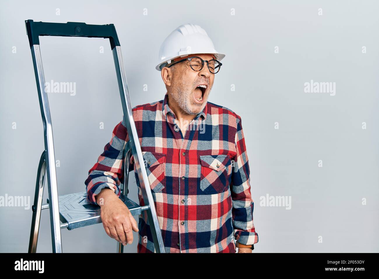 Handsome mature handyman close to construction stairs wearing hardhat ...