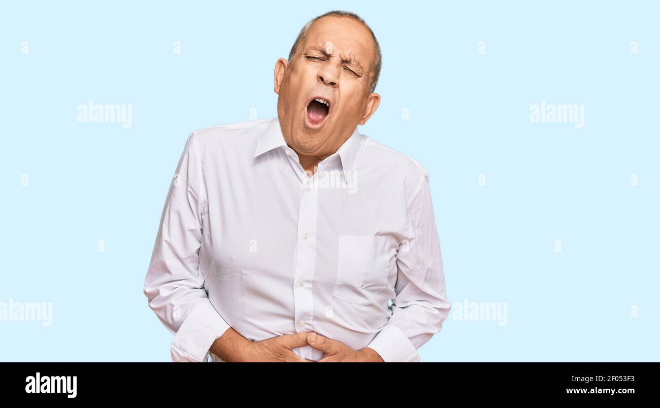 Handsome senior man wearing elegant white shirt with hand on stomach ...