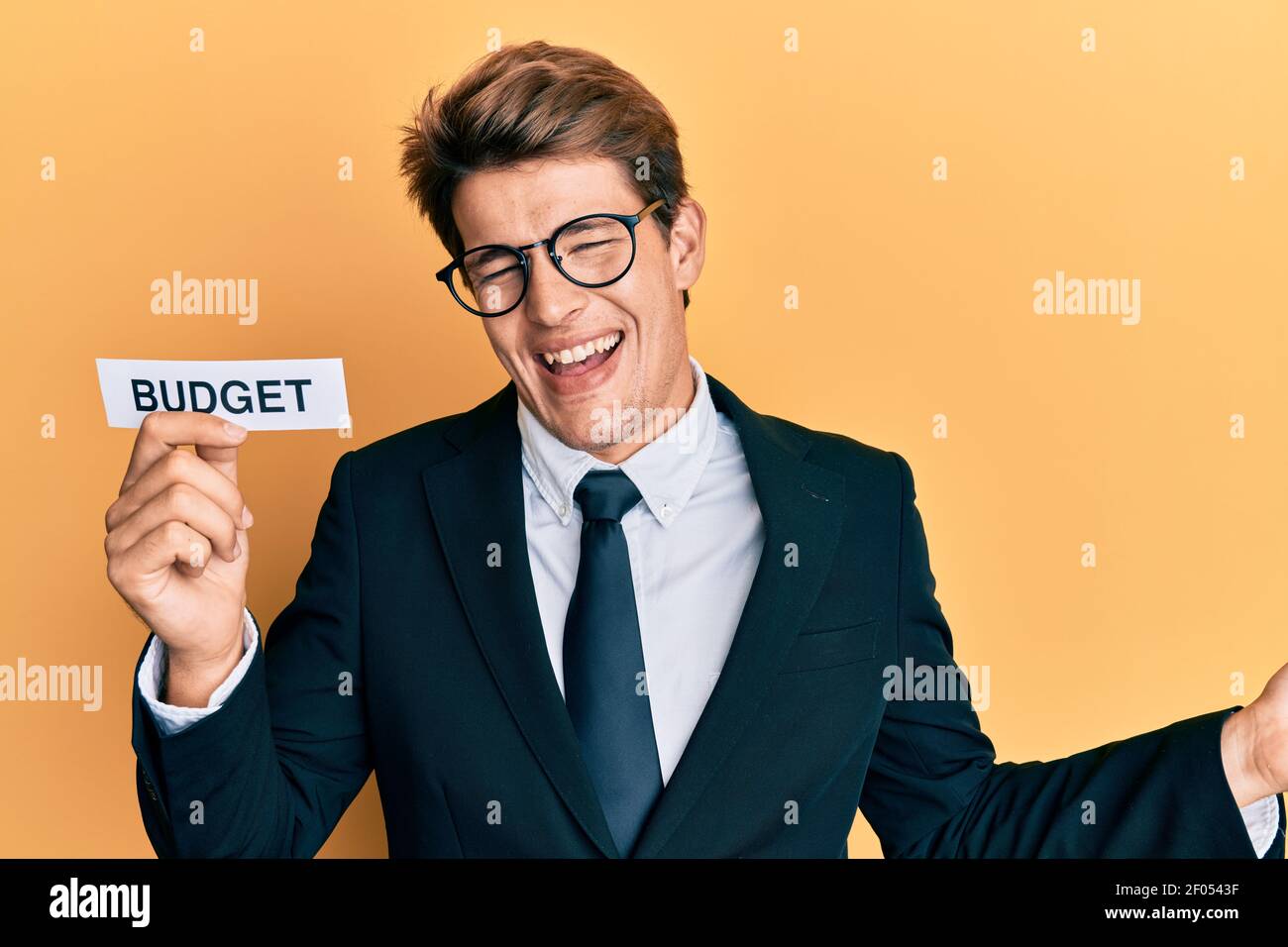 Handsome caucasian business man holding budget word on paper ...